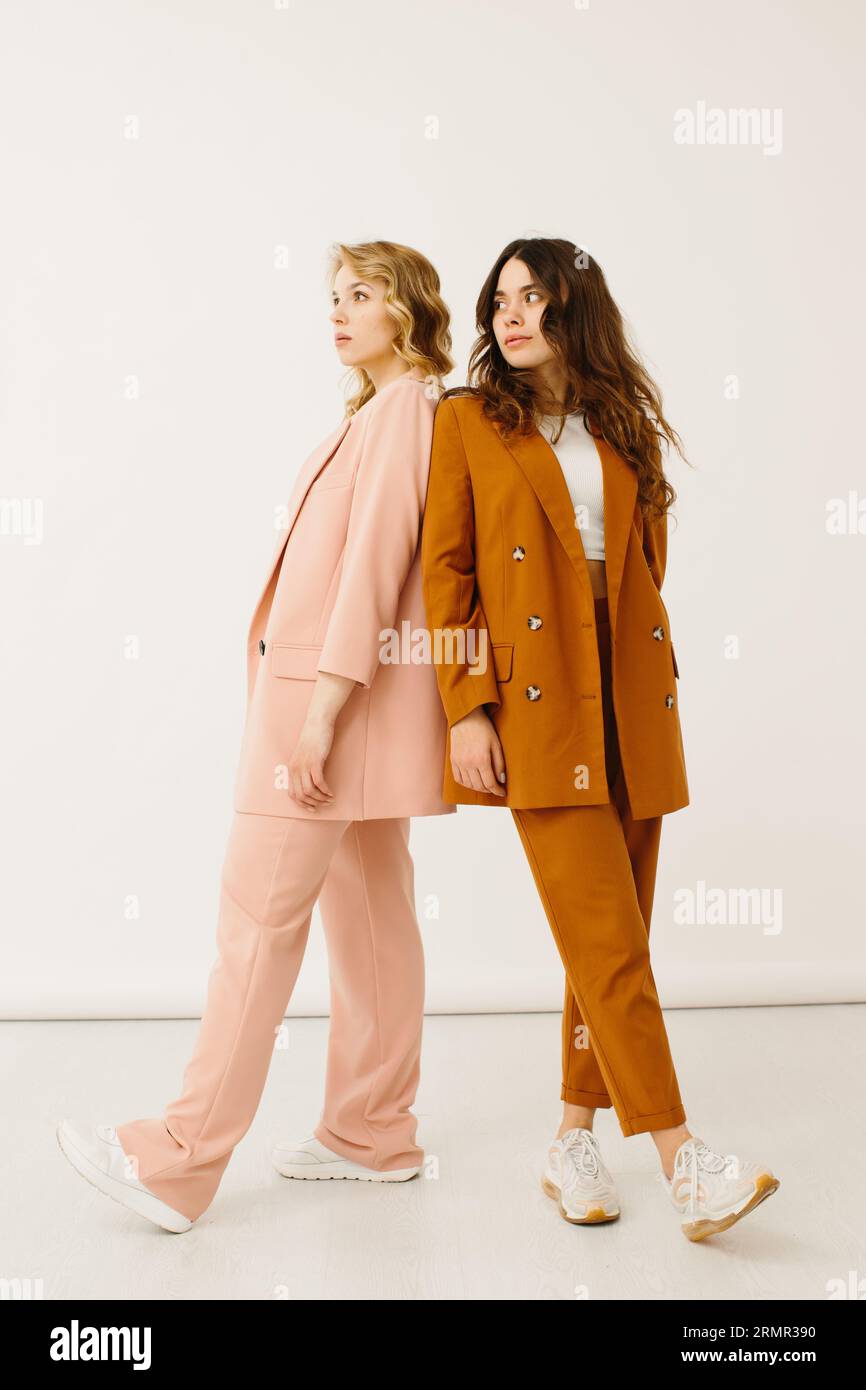 Stylish young women in pastel outfits standing together, fashion ...