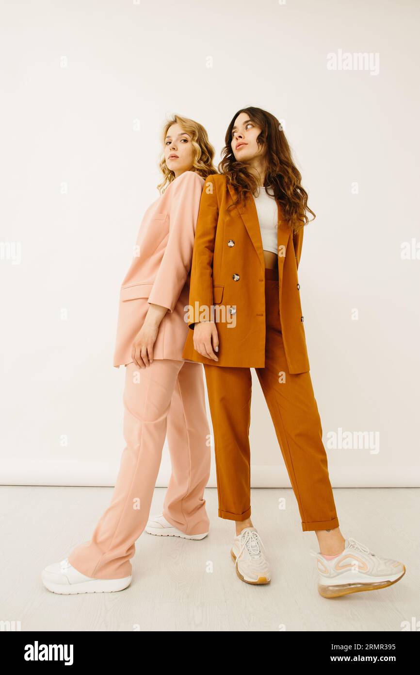 Stylish young women in pastel outfits standing together, fashion ...