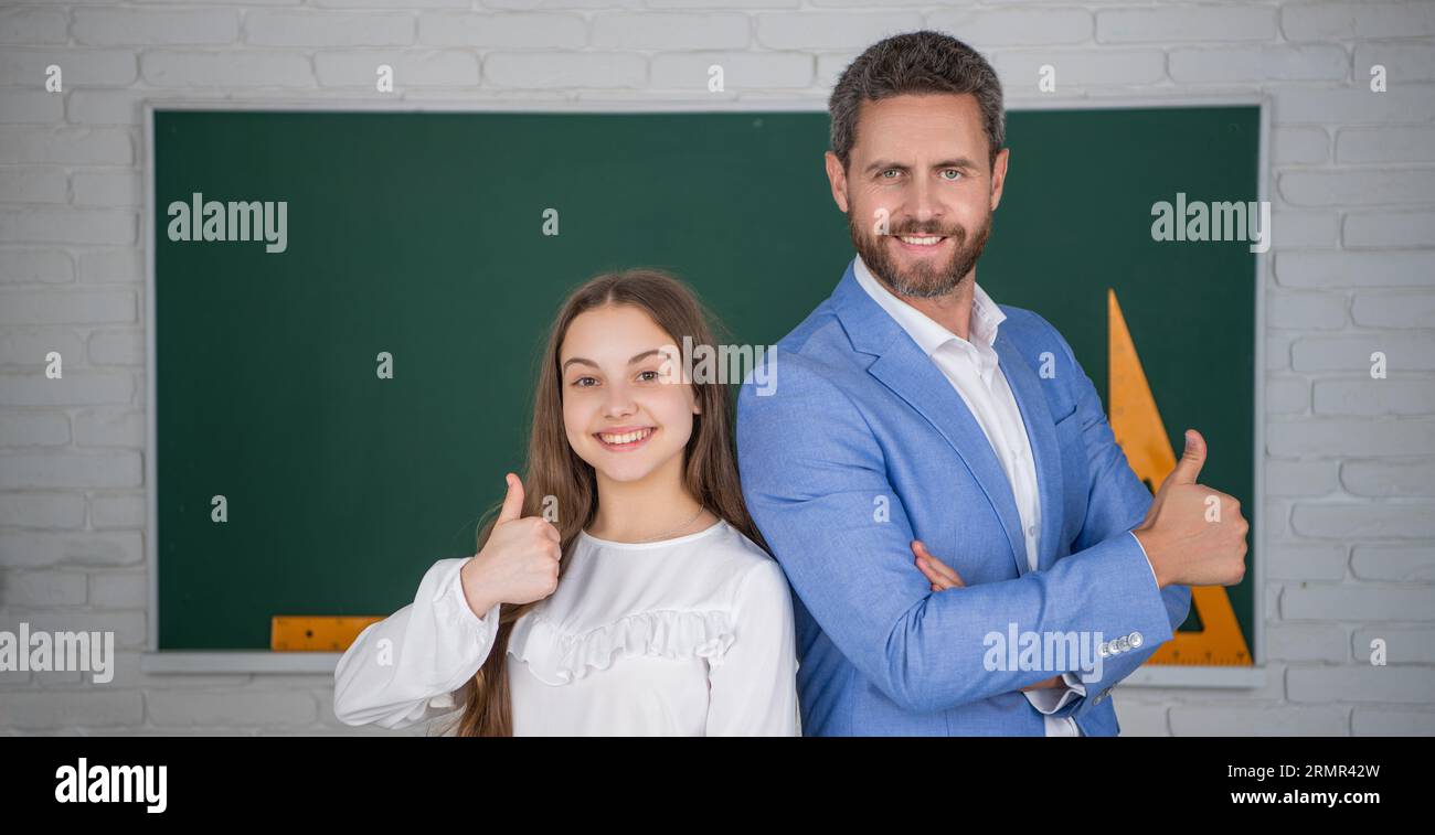 happy child standing at blackboard with teacher Stock Photo - Alamy