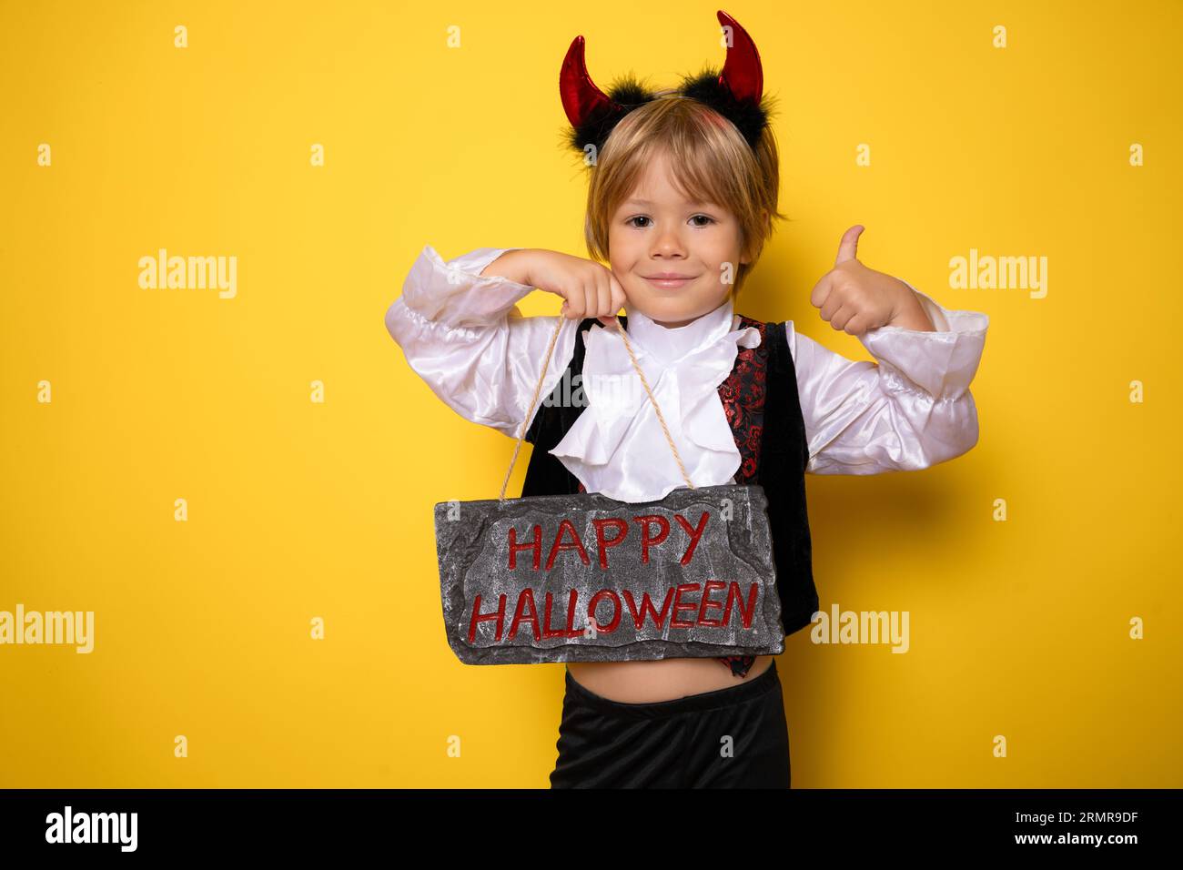 little boy dressed as a vampire on halloween isolated over yellow ...
