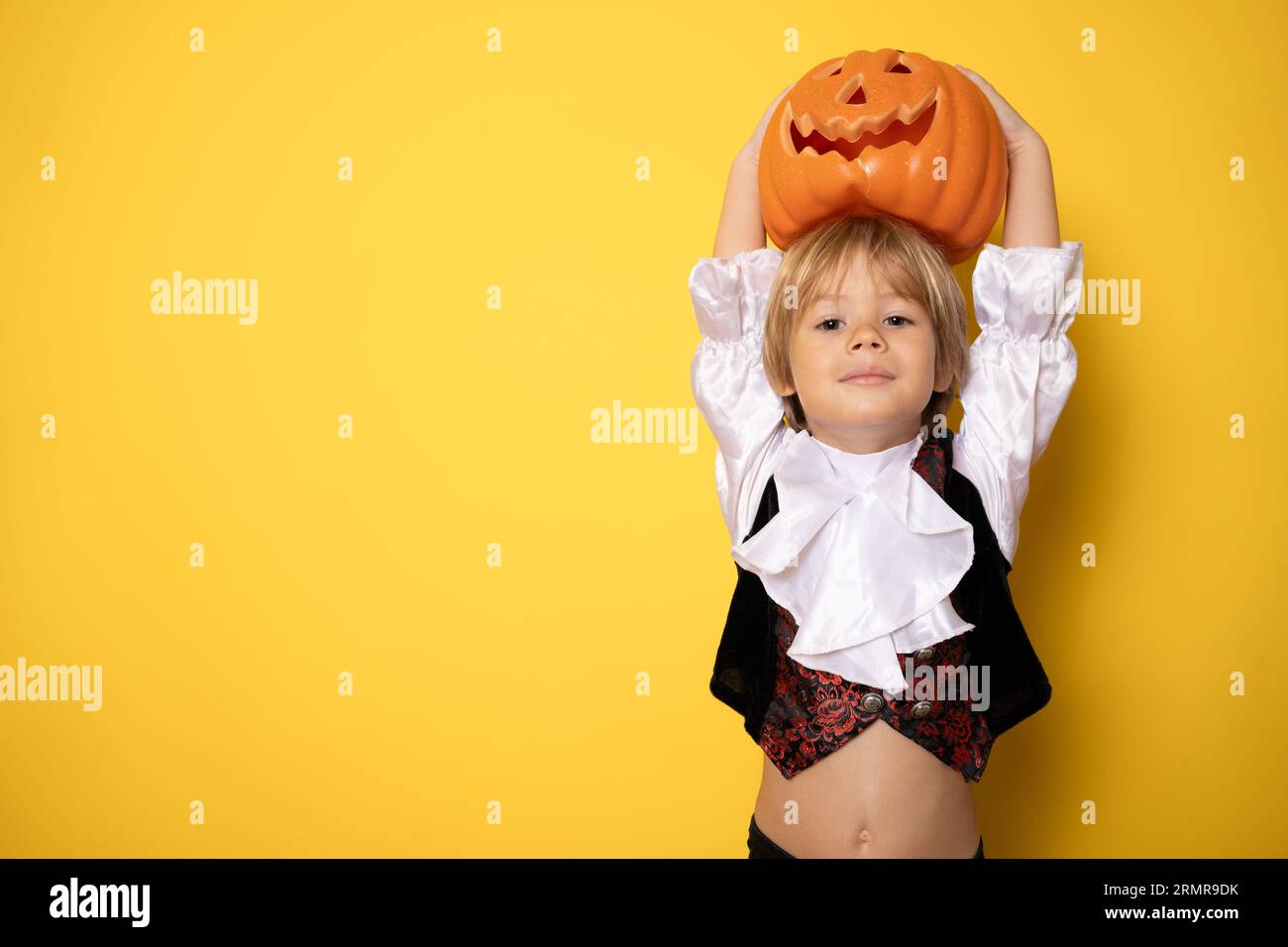little boy dressed as a vampire on halloween isolated over yellow ...