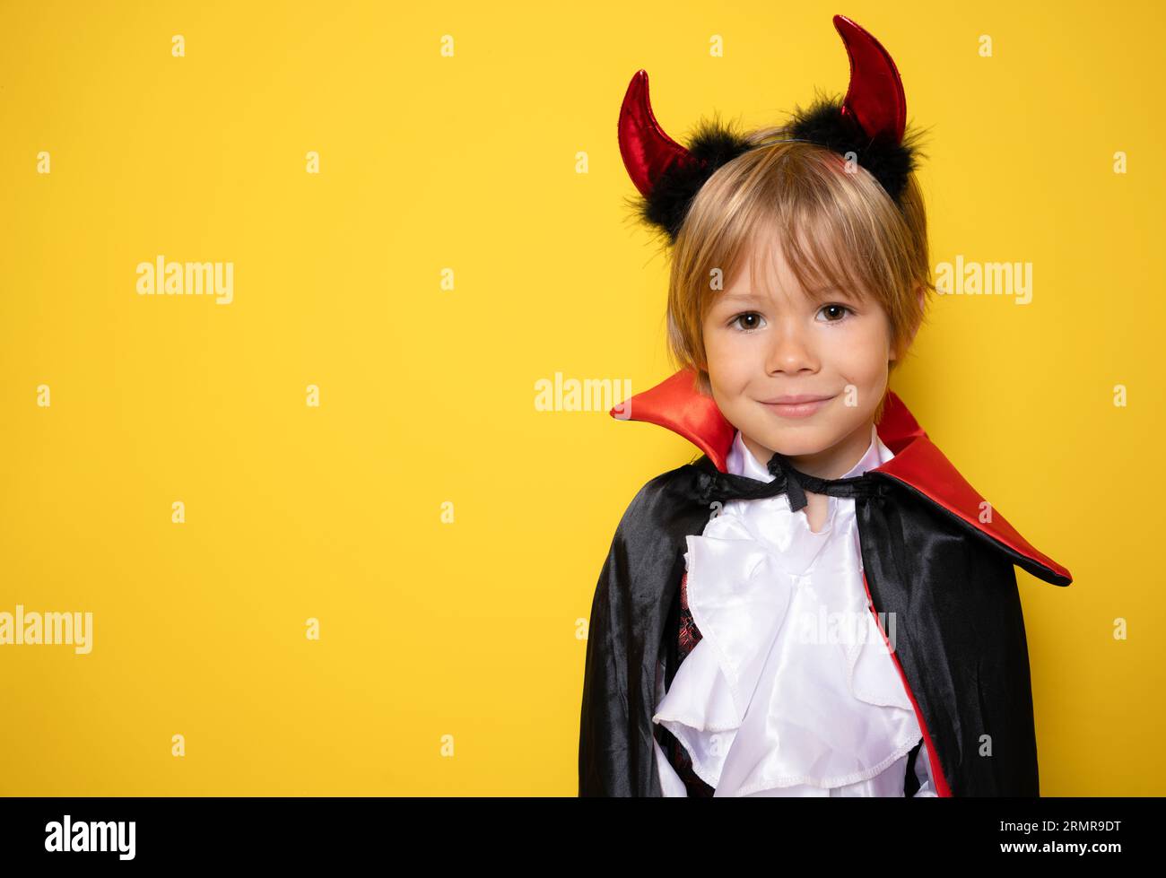 little boy dressed as a vampire on halloween isolated over yellow ...