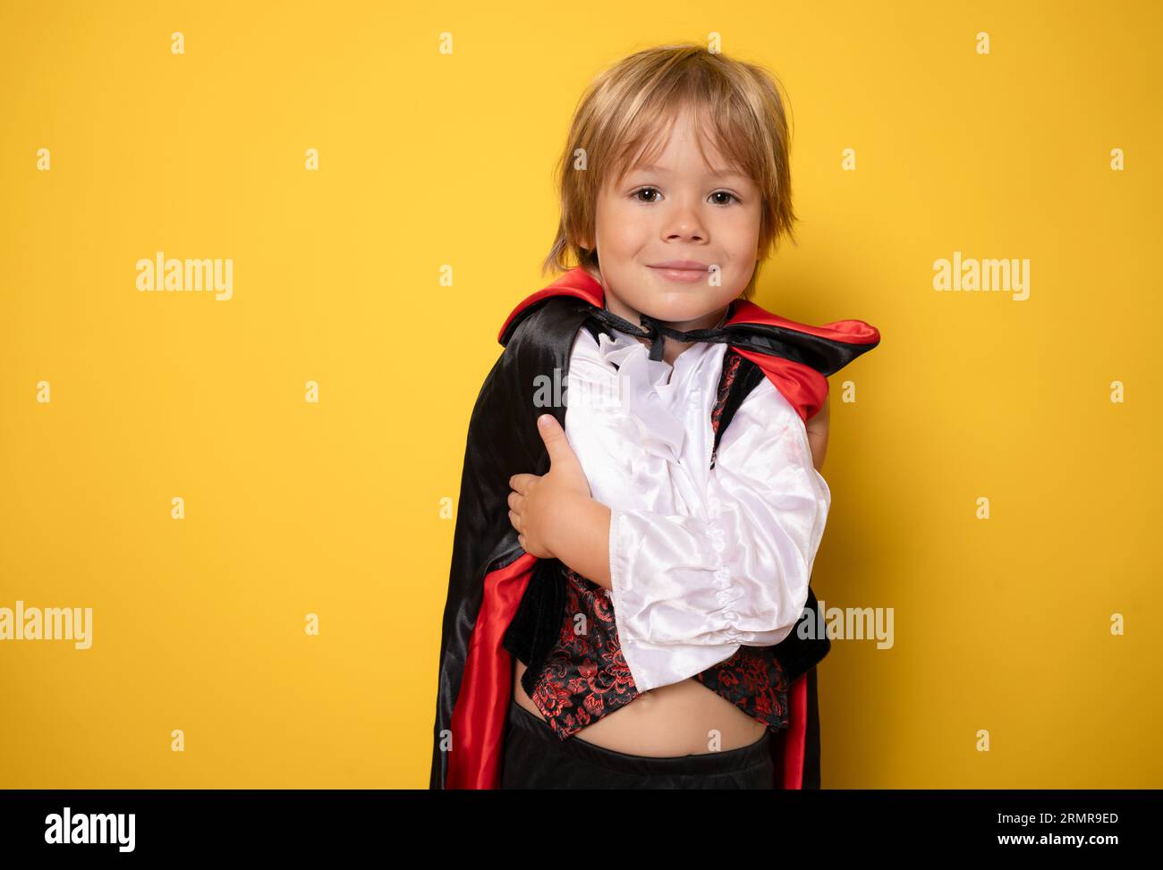 little boy dressed as a vampire on halloween isolated over yellow ...