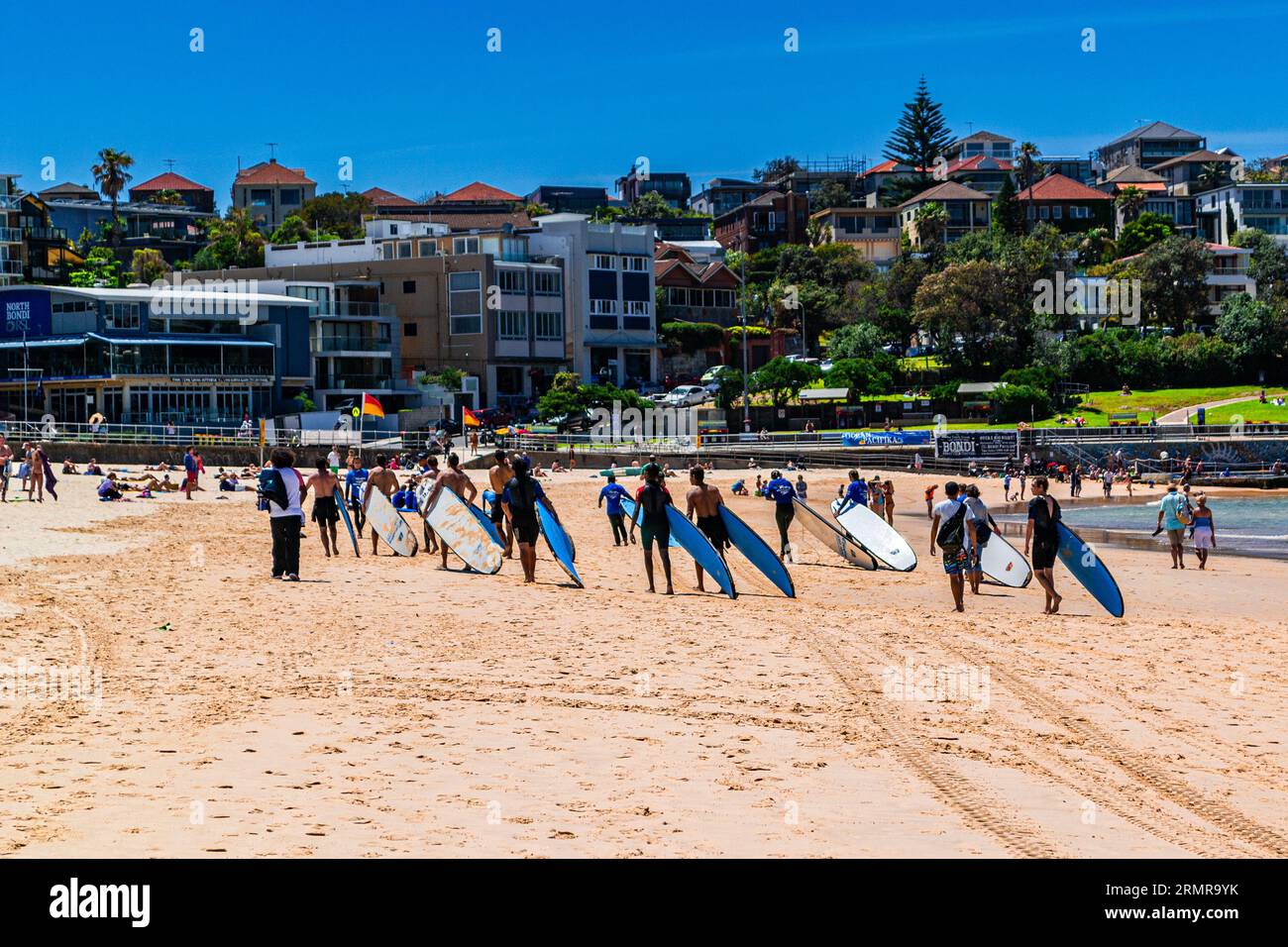 Surfers head back up the beach, after a surf lesson on a beautiful ...