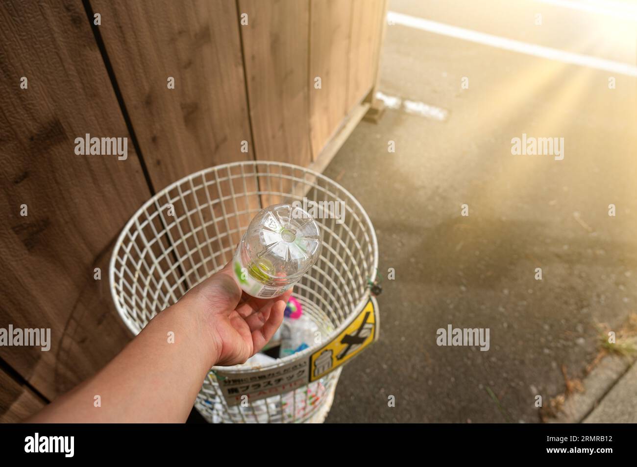 People throwing a plastic bottle in to a recycle bin. Women sorting ...