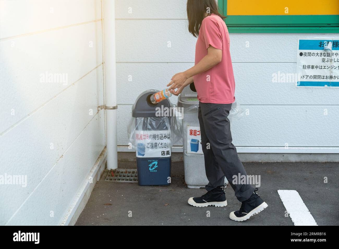 People throwing a plastic bottle in to a recycle bin. Women sorting waste before put into a ...