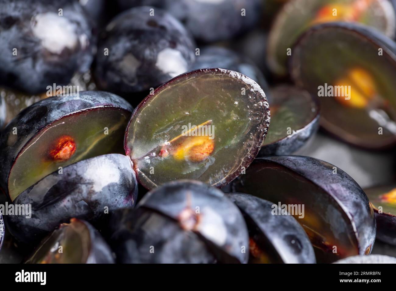 sweet ripe black grapes cut in half, wet dark grapes cut into pieces ...
