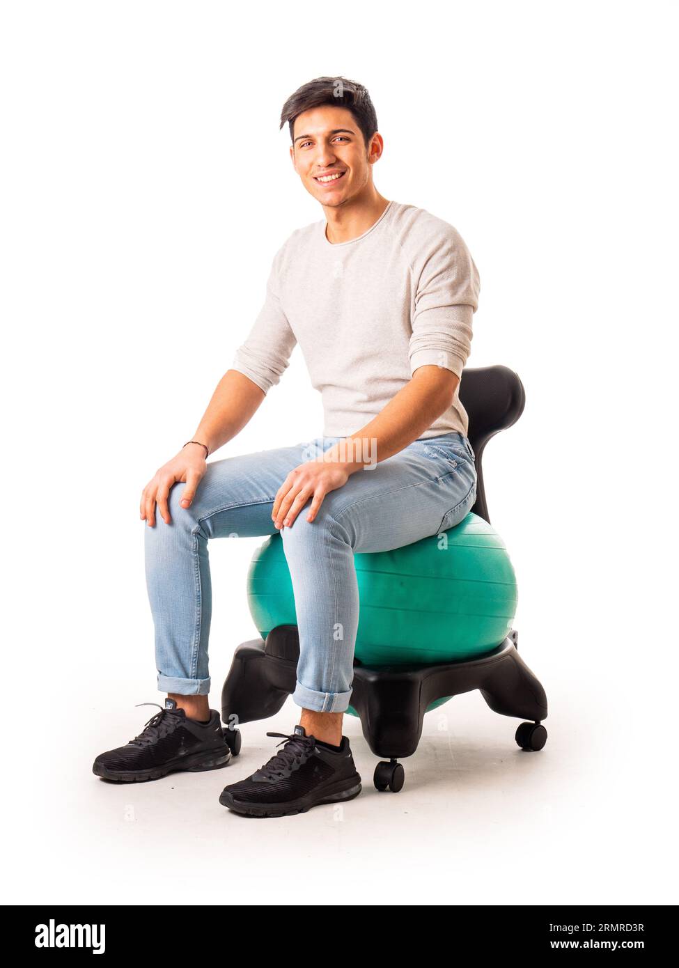 A young smiling man sitting on an ergonomic chair with an inflatable ...