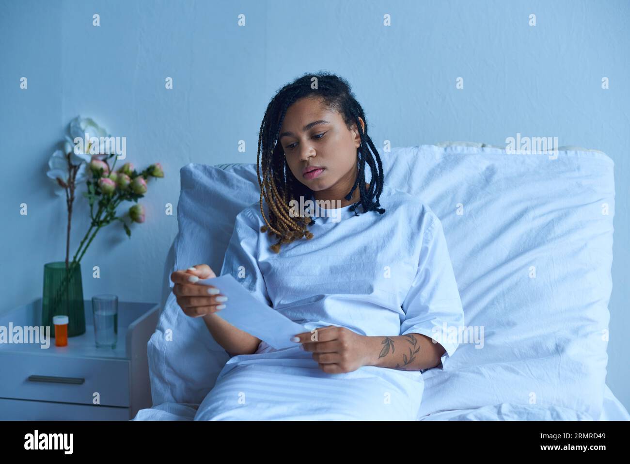 private ward, sad african american woman in hospital gown looking at ...