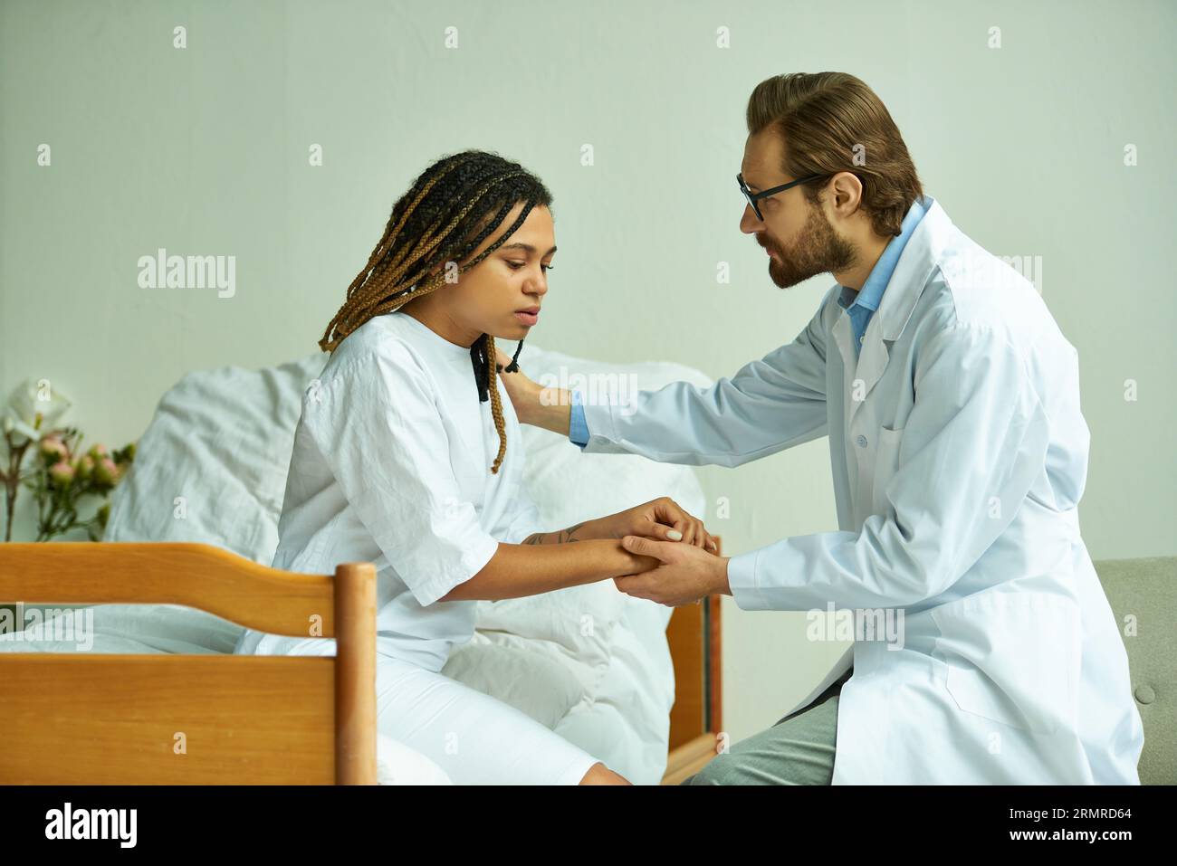 male doctor holding hands of african american woman, comforting patient ...