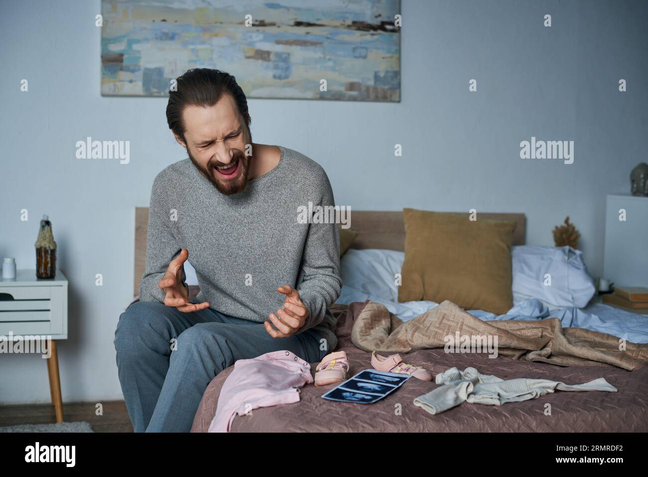 grief, depressed man crying and screaming near baby clothes and ...