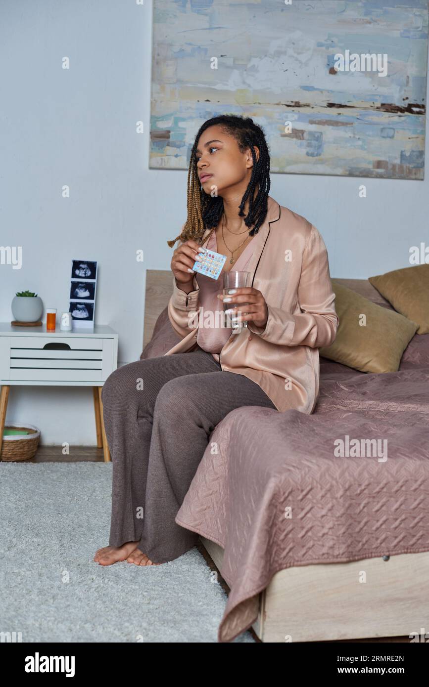 african american woman holding glass of water and birth control pills ...