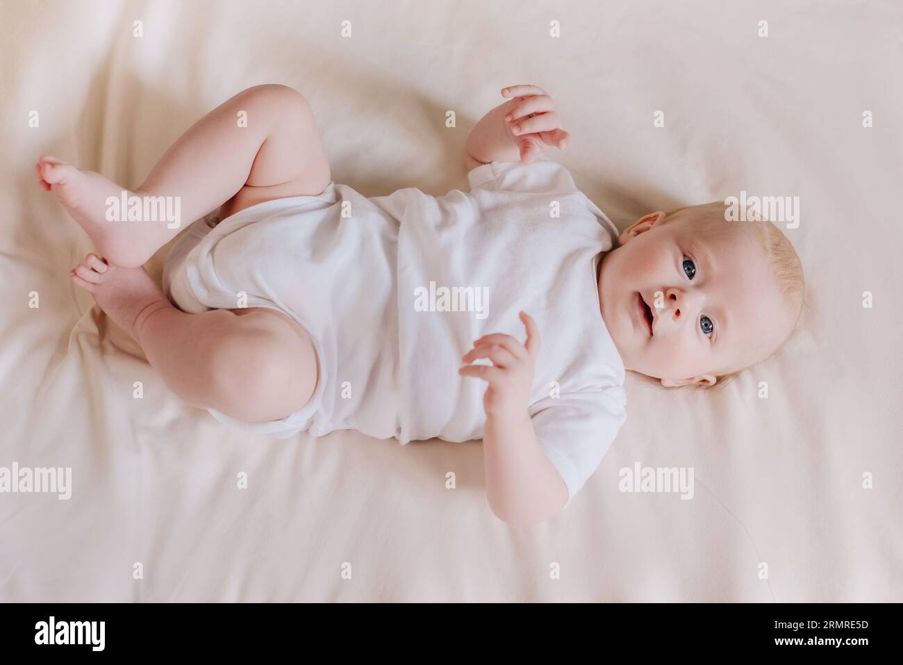 Top view portrait of cheerful cute newborn baby lying down alone on ...