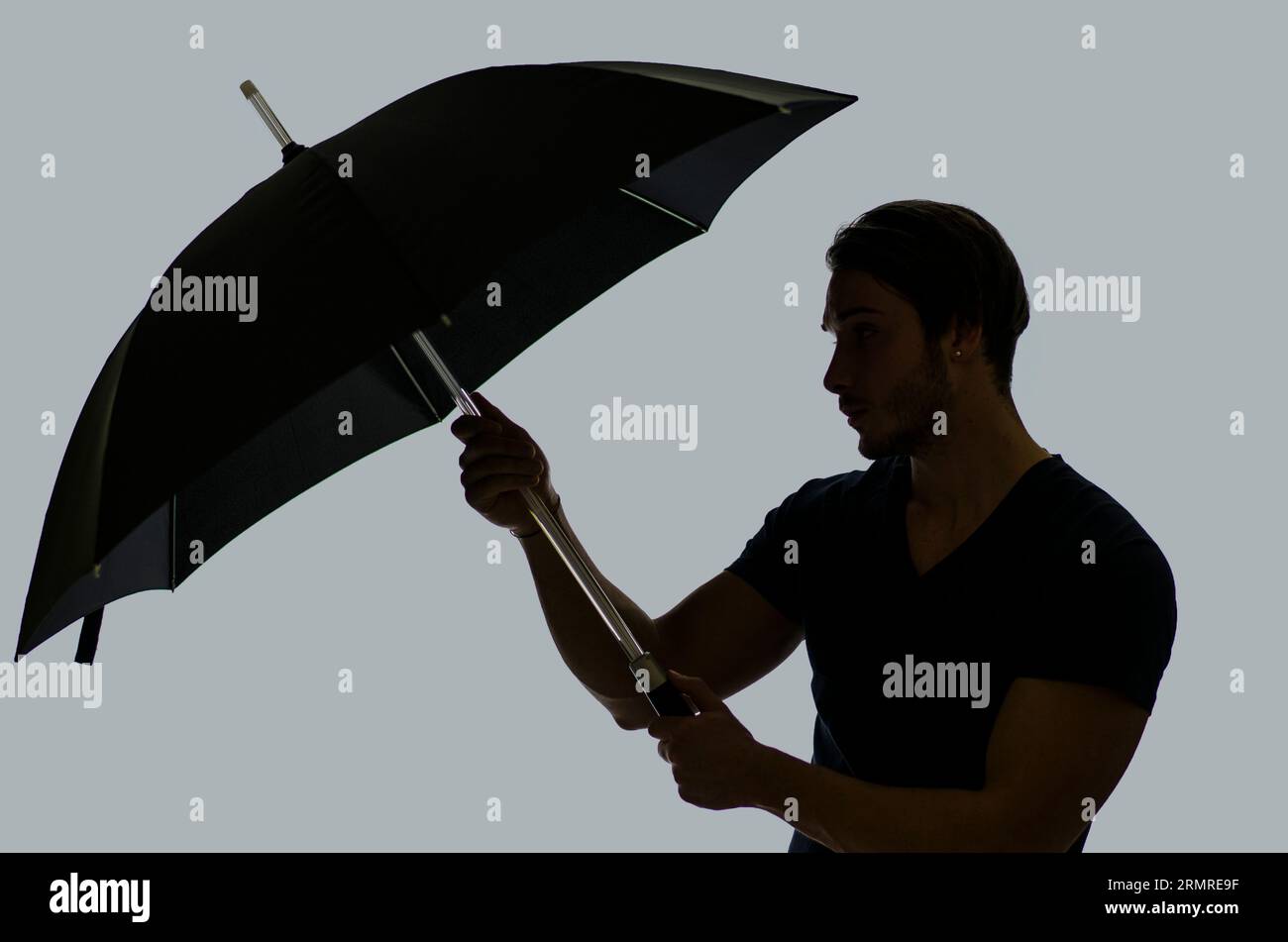 A man holding a black umbrella in his hand Stock Photo - Alamy
