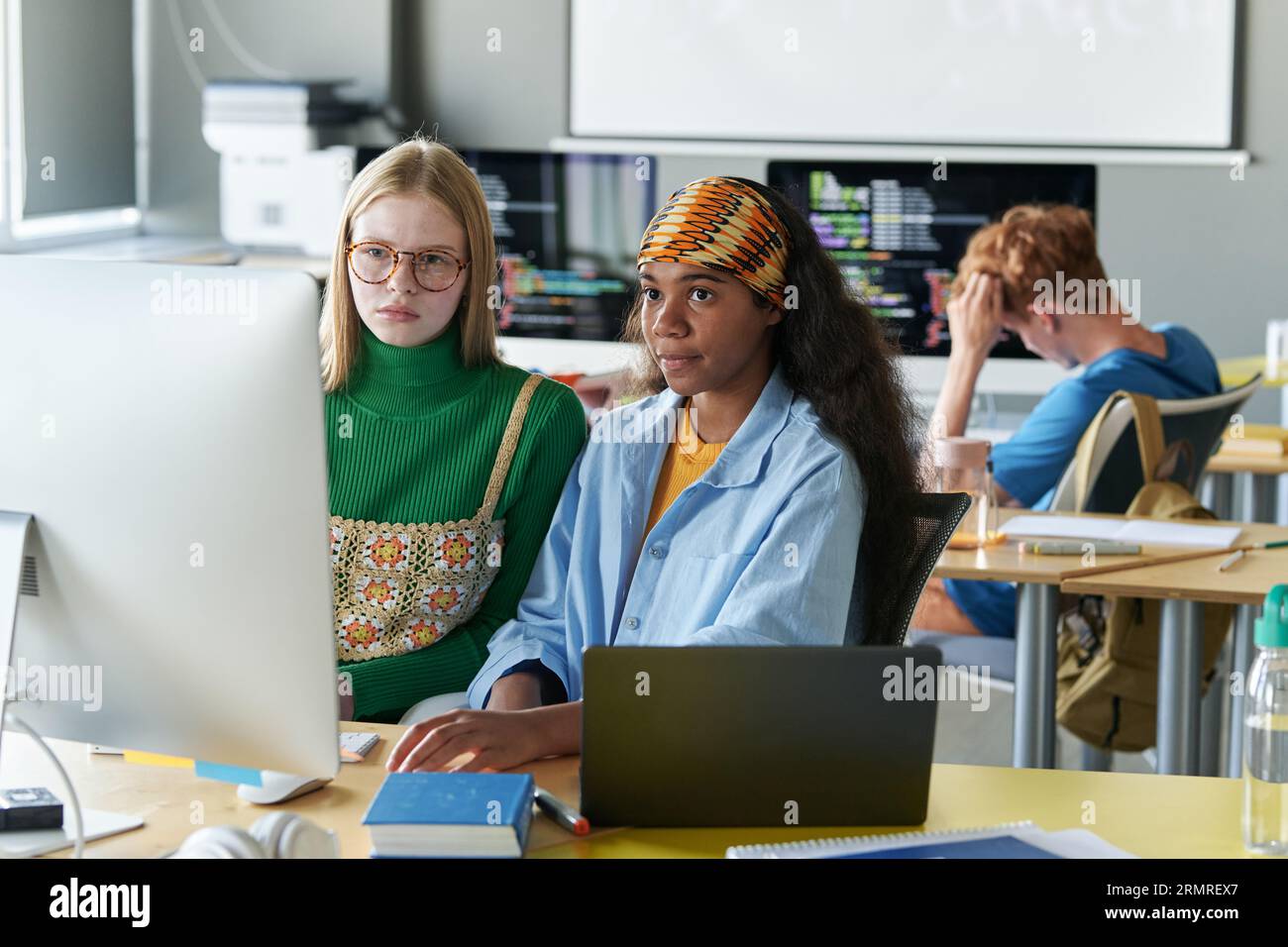 Students sitting in front of computer monitor and watching presentation ...
