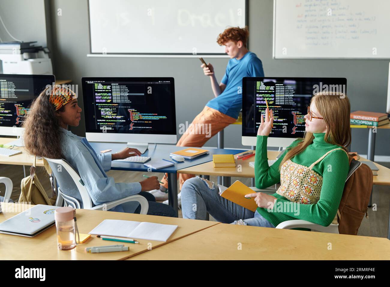 Group of students sitting at desk with computers during IT lesson in ...