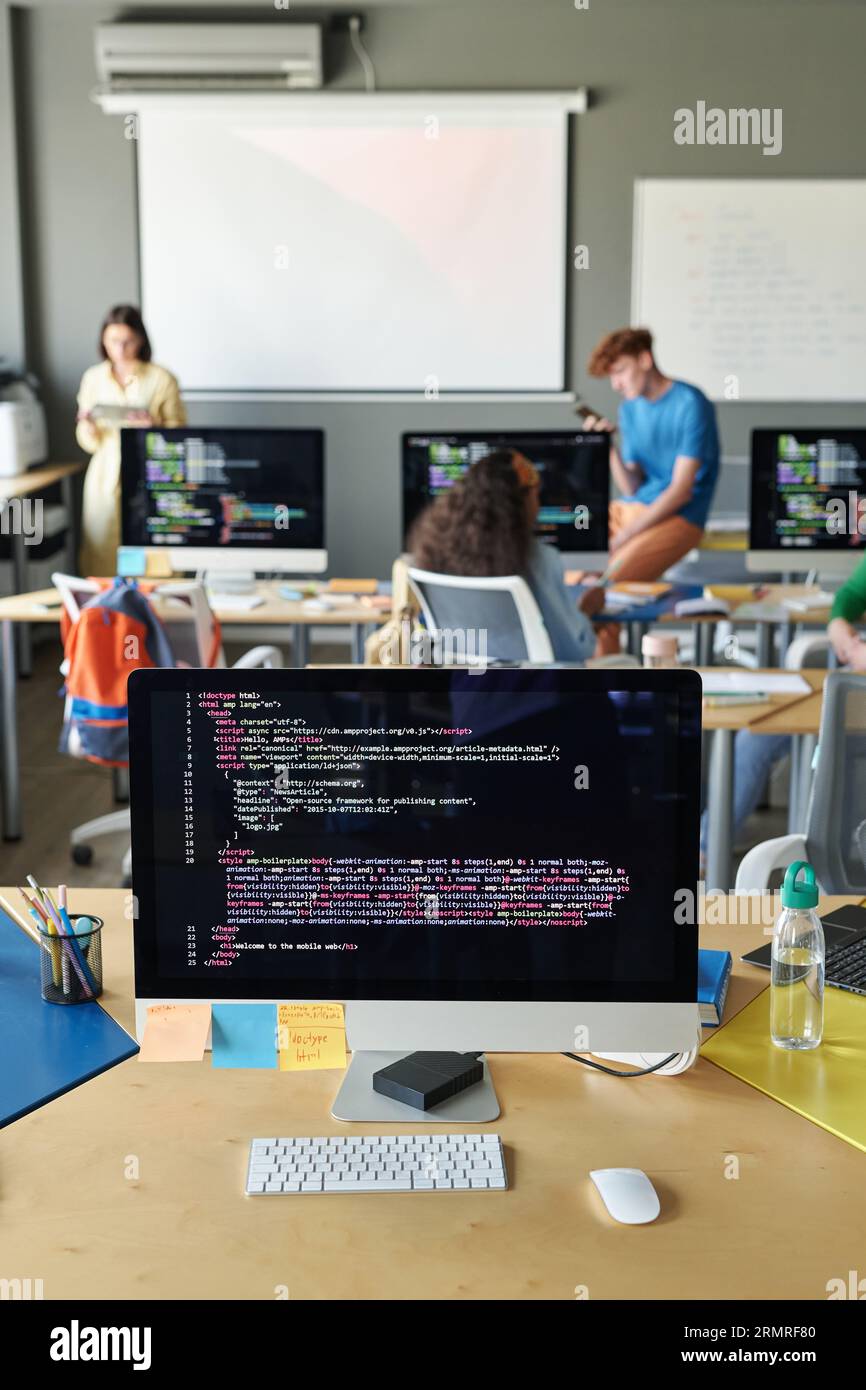 Vertical image of computer with codes on monitor standing on desk in ...