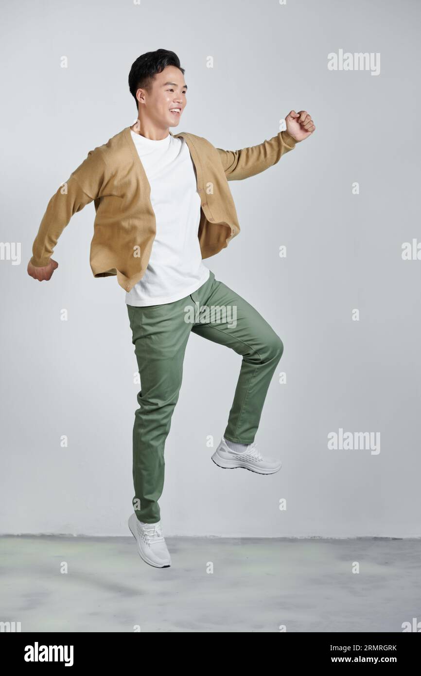 Happy energetic young Asian man jumping yelling and clenching fists ...