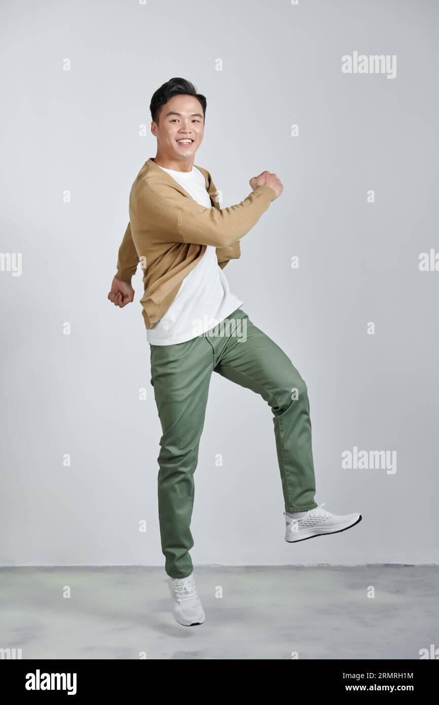 Happy excited young Asian man jumping isolated on white studio ...