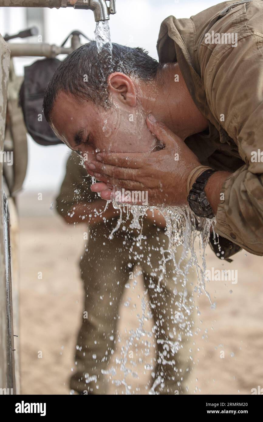 GAZA BORDER, July 24, 2014 -- An Israeli soldier washes his face at an ...