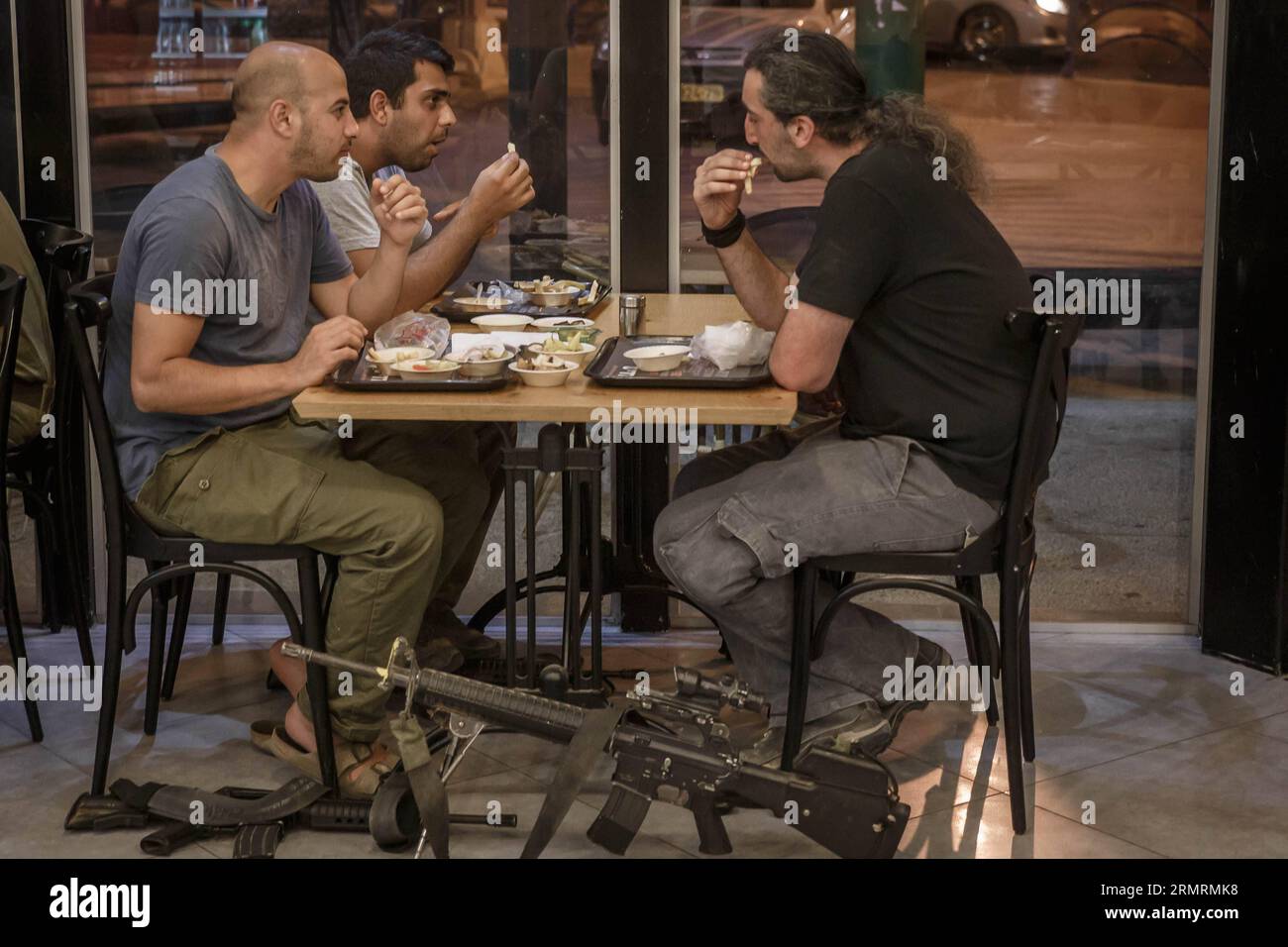Israeli reserve soldiers enjoy their meals at a local restaurant in ...