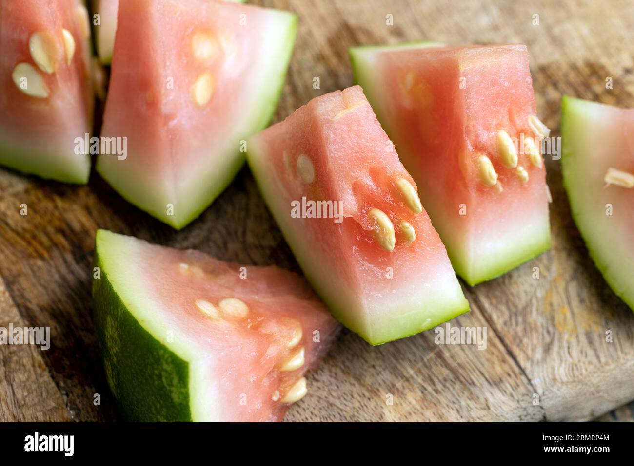 Unripe watermelon of small size with large white seeds and light pink ...