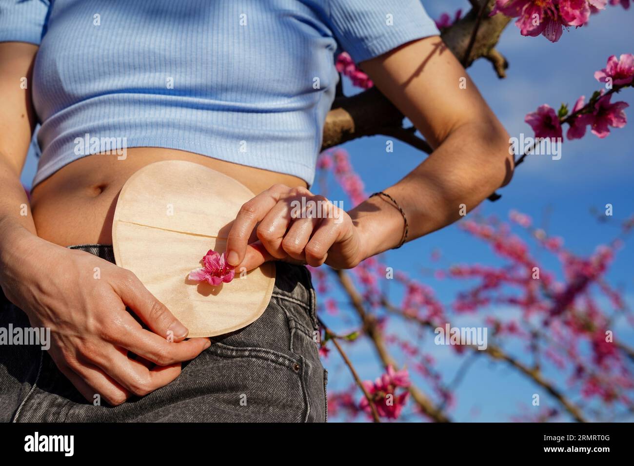 Unrecognizable woman with ostomy bag decorating it with a pink flower ...
