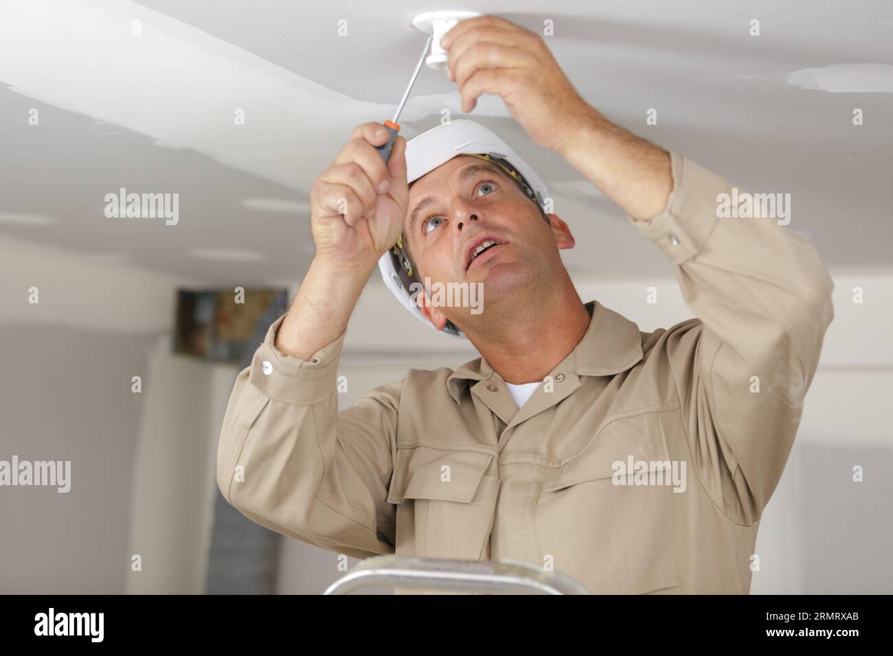 technician is fixing a light bulb at the ceiling Stock Photo - Alamy