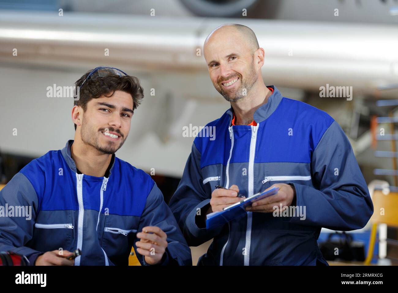 portrait of two smiling professional car mechanics at workshop Stock ...