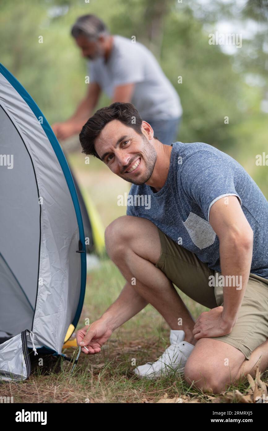 men on camping trip assembling their tents Stock Photo - Alamy