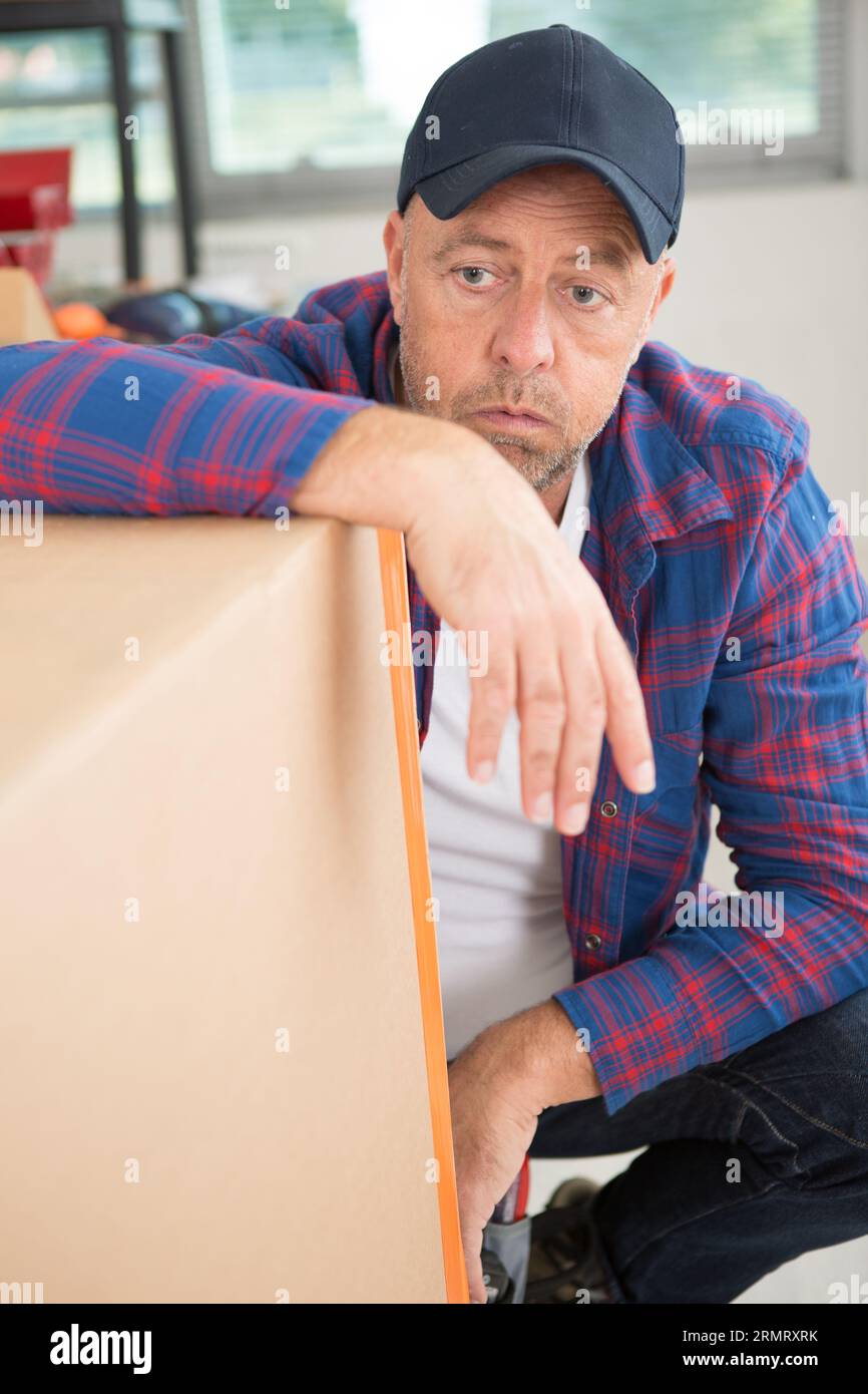 mature exhausted delivery man next to boxes Stock Photo - Alamy