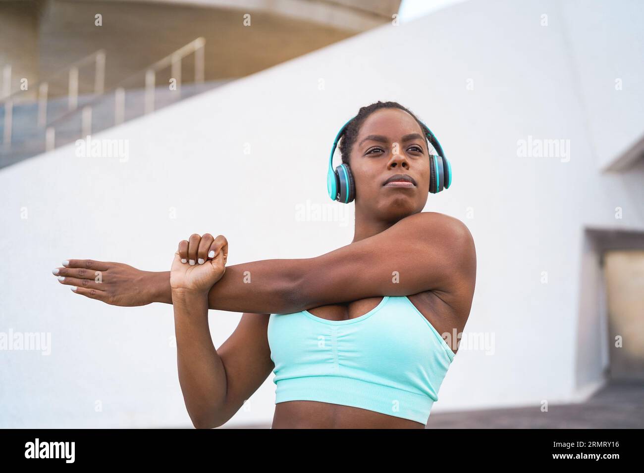 African fit woman listening music with headphones while doing ...