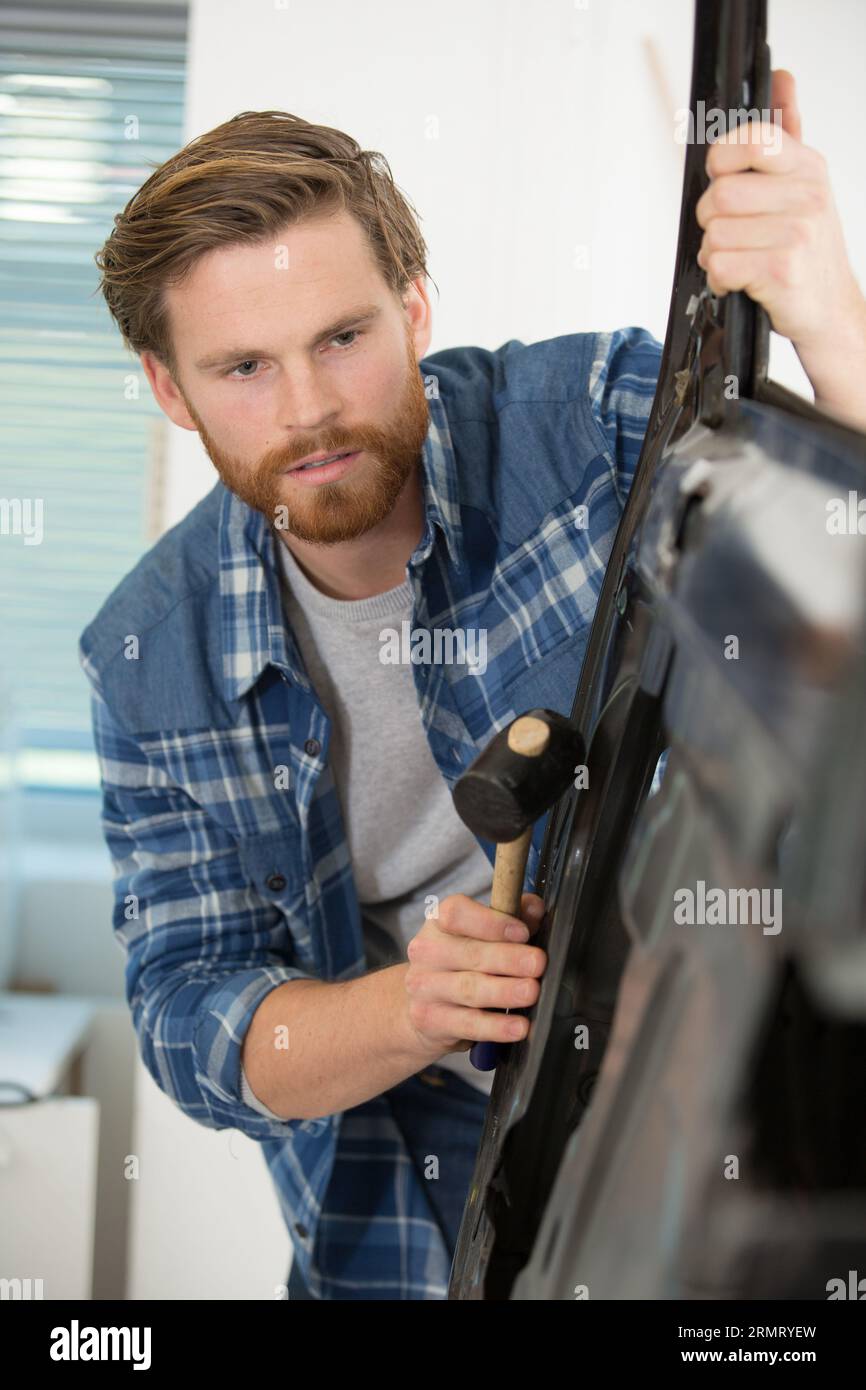 man repairing car door with a rubber mallet Stock Photo - Alamy