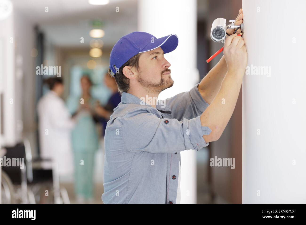man fitting a cctv in hospital Stock Photo - Alamy