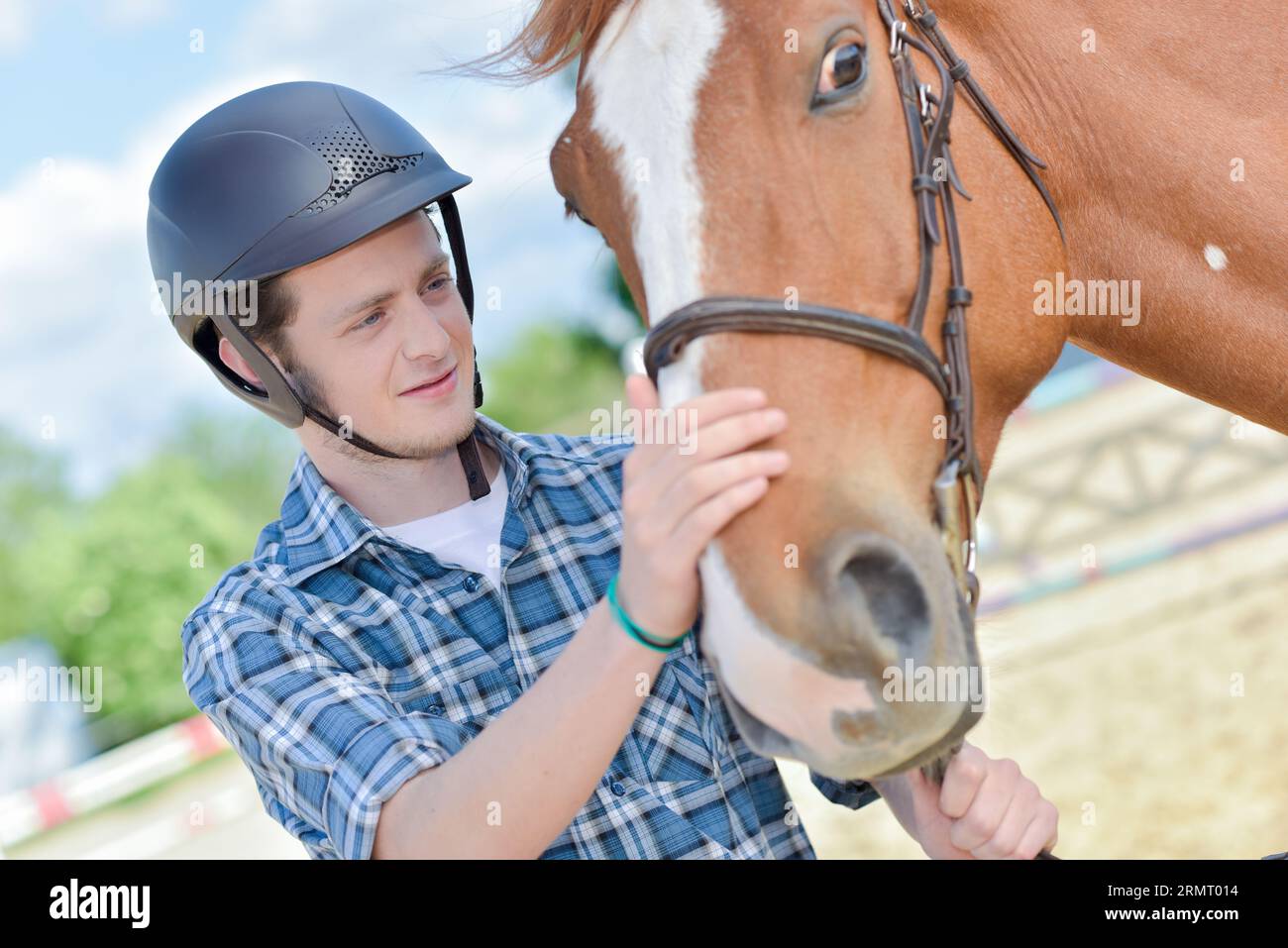 Man in riding hat stroking horse Stock Photo - Alamy