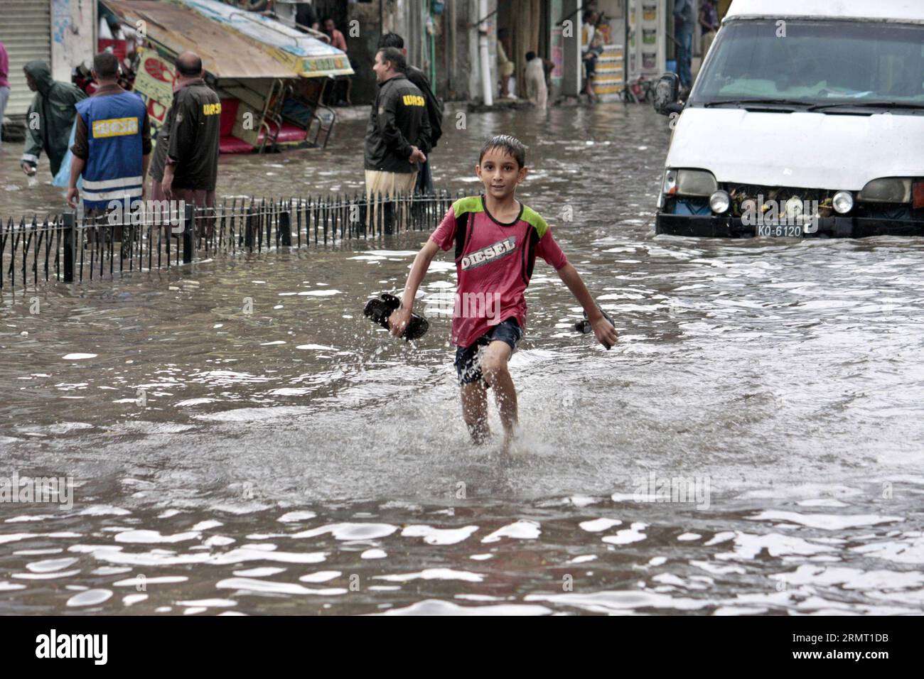 A Pakistani boy crosses flooded water after heavy monsoon rain in ...