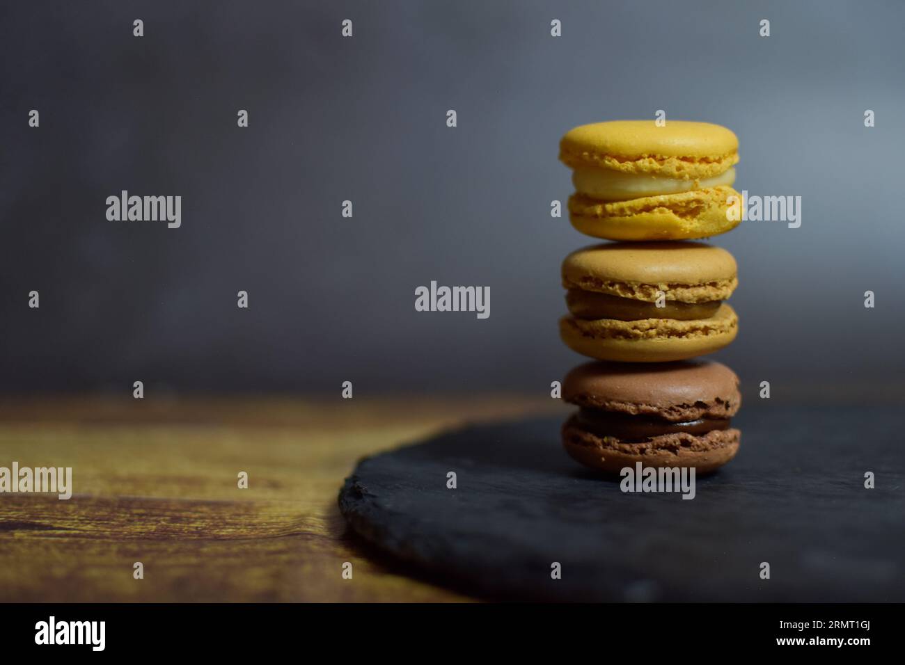 Macarons brown and yellow toned stacked on slate plate and black ...