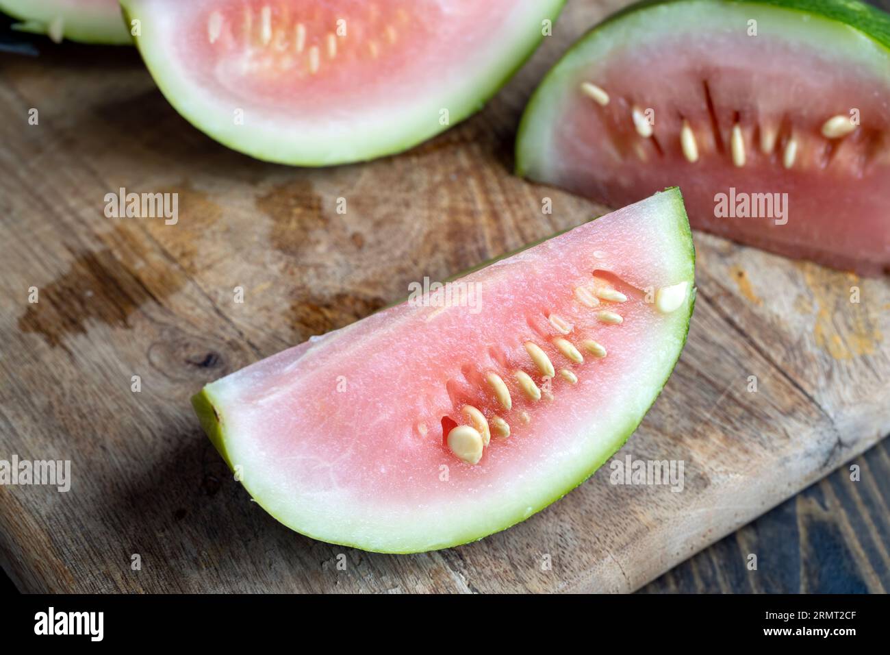 Unripe watermelon of small size with large white seeds and light pink ...