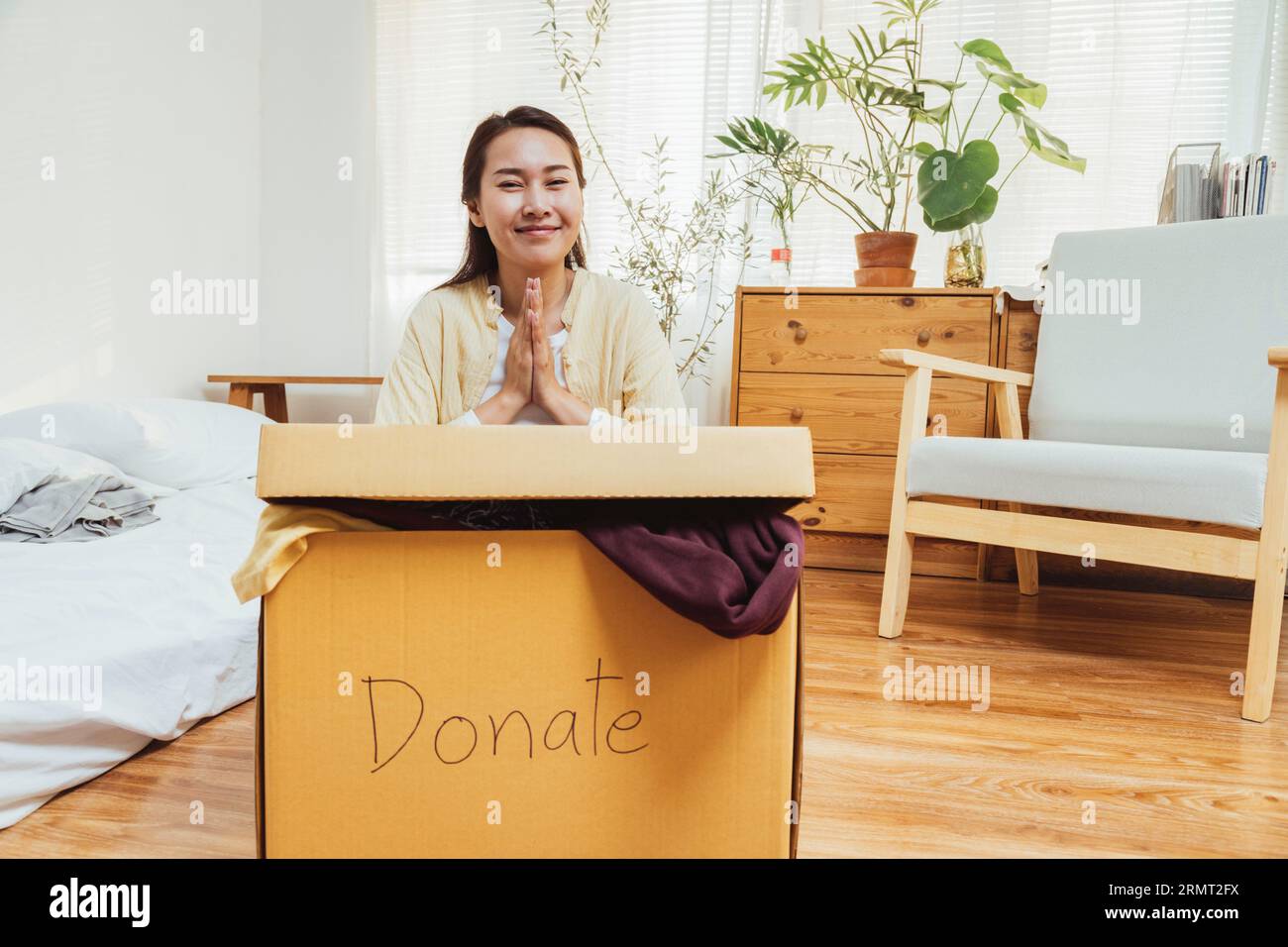 volunteer asian woman putting unused clothes into cardboard boxes for ...
