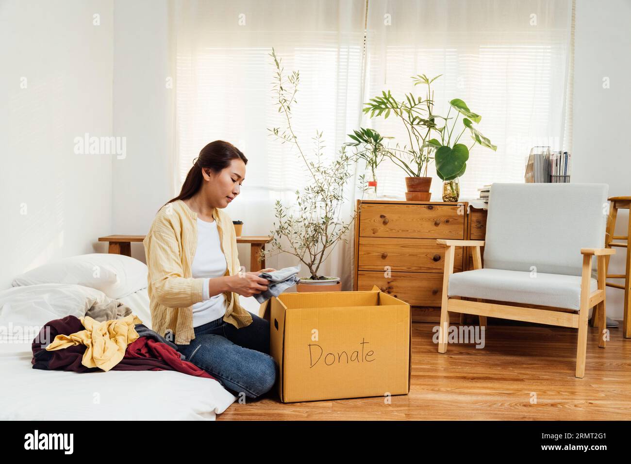 volunteer asian woman putting unused clothes into cardboard boxes for ...