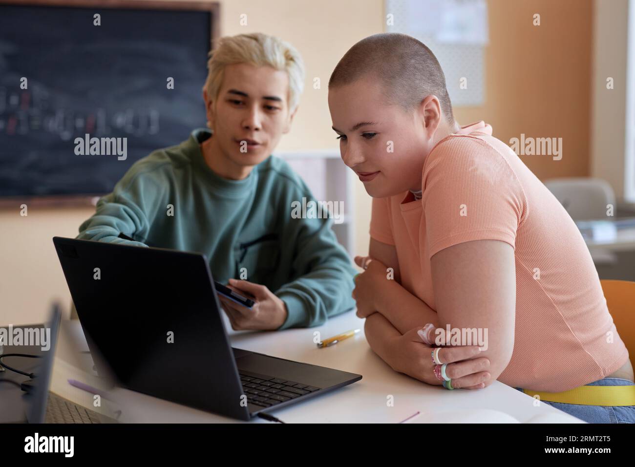 Young woman looking at laptop screen while Asian guy making ...