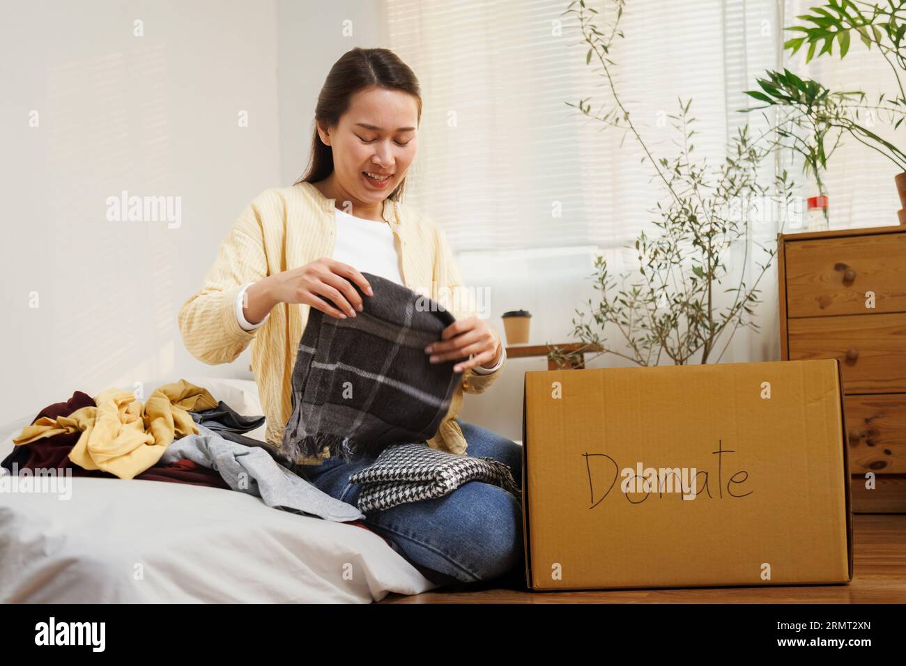 volunteer asian woman putting unused clothes into cardboard boxes for ...