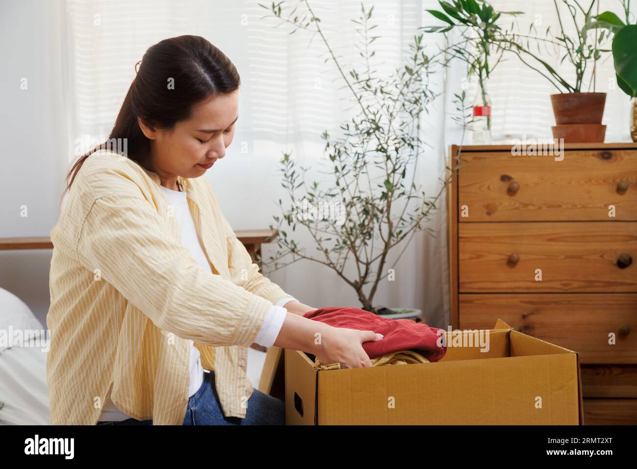 volunteer asian woman putting unused clothes into cardboard boxes for ...