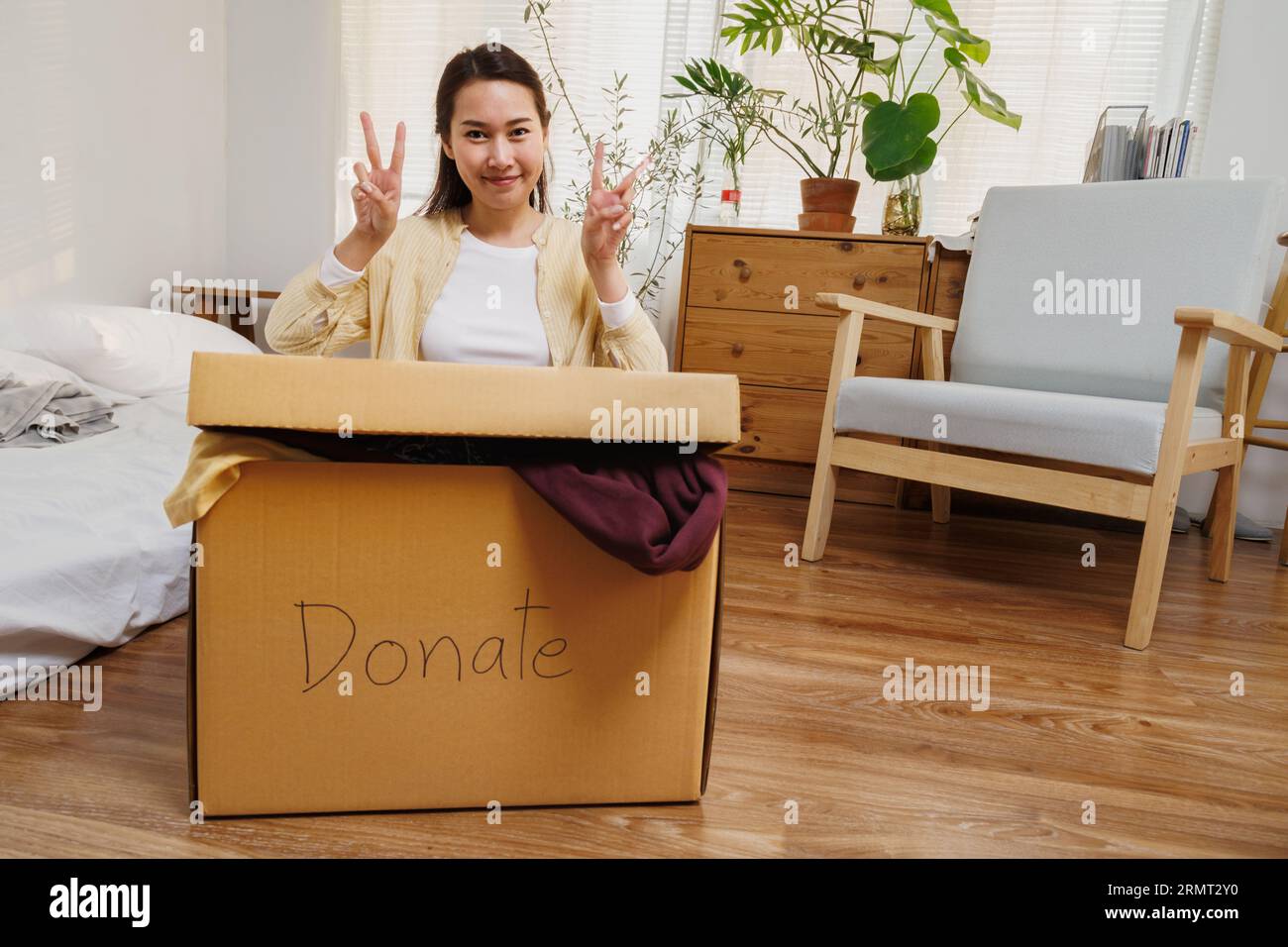 volunteer asian woman putting unused clothes into cardboard boxes for ...