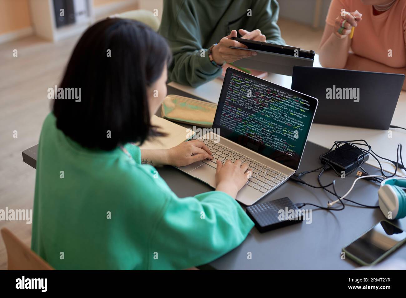Young female student typing on laptop keyboard while decoding data on ...