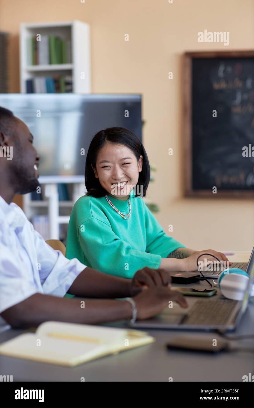 Young cheerful Asian female student typing on laptop keyboard and ...