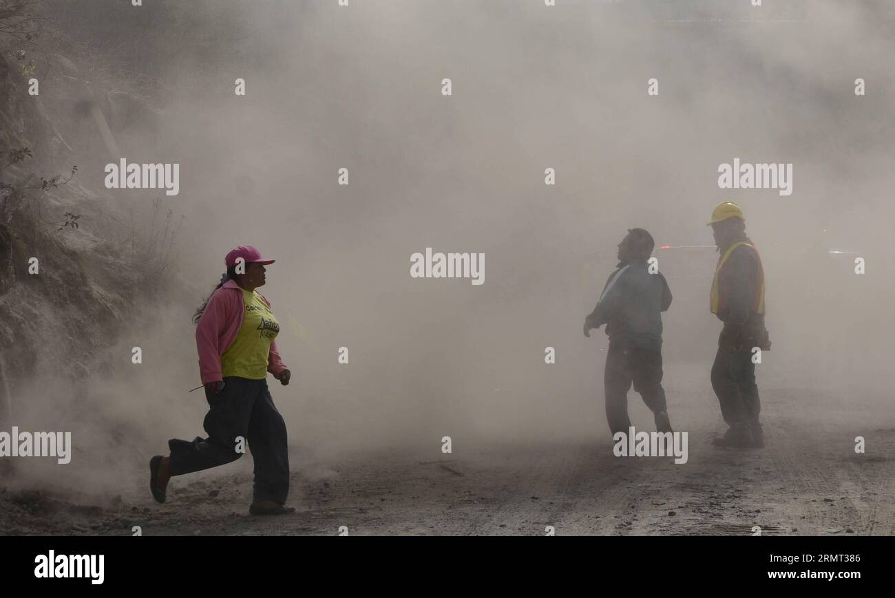 QUITO, August 12, 2014 -- People walk amid dust at the site of a ...