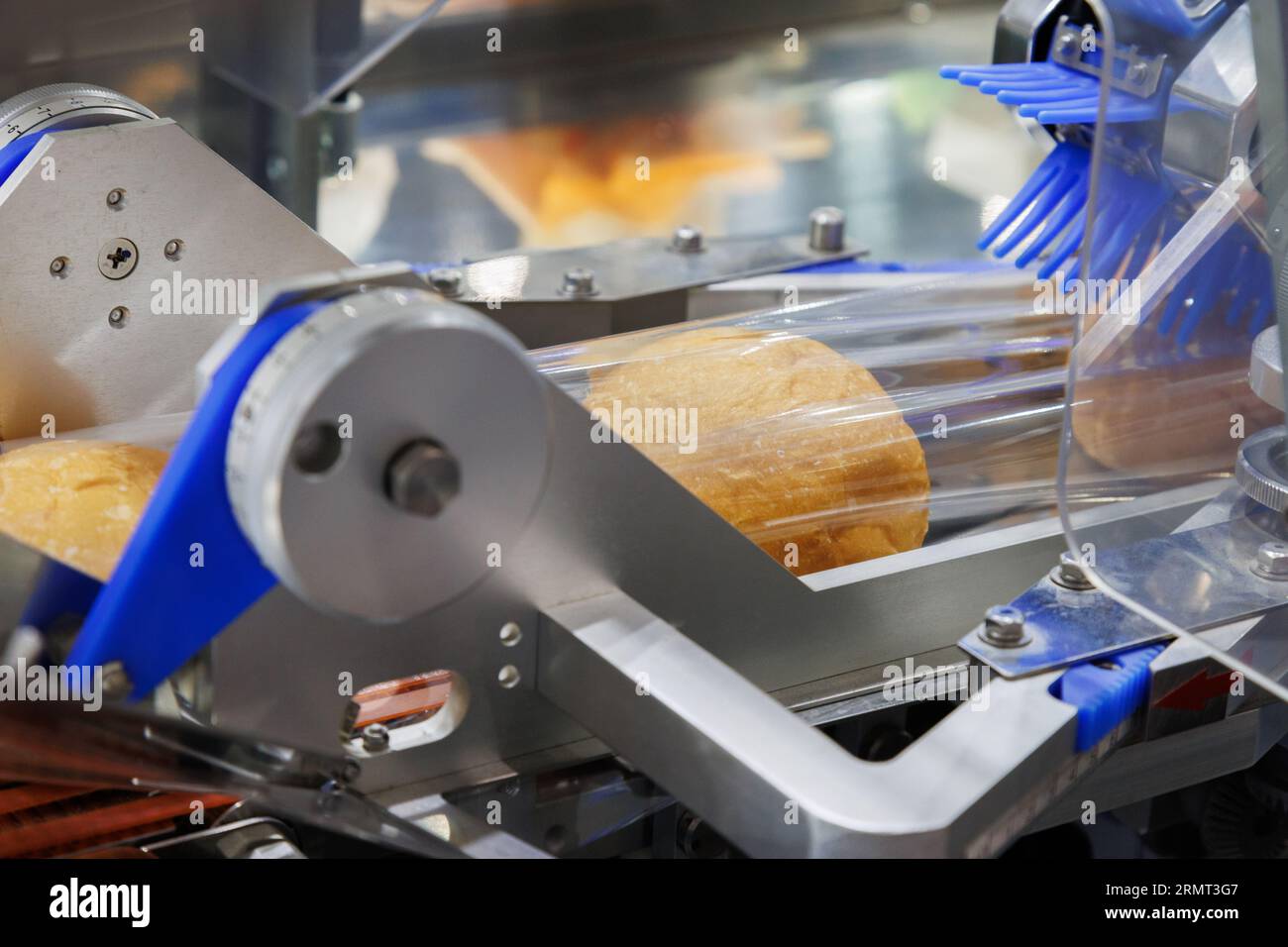 baked bread in food grade plastic bag on conveyor belt moves to seal in ...