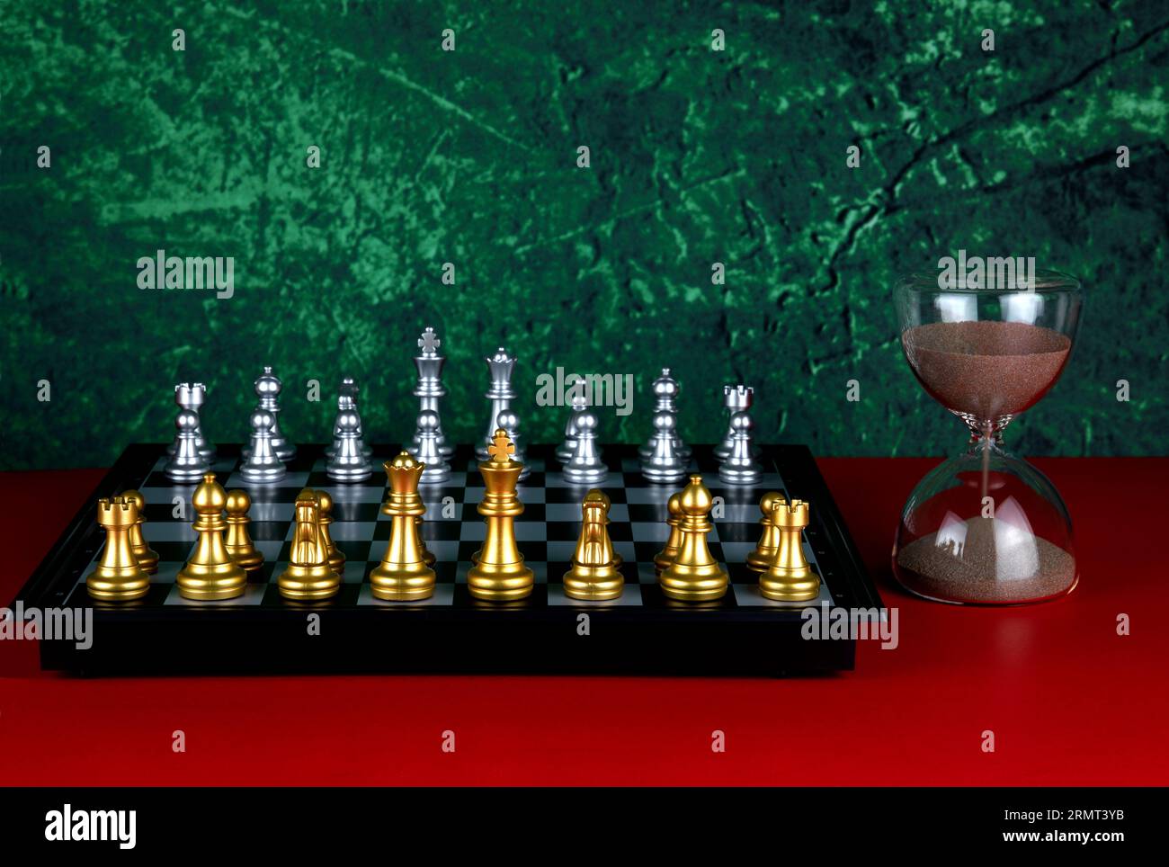 Chess board and silver and gold chess pieces with hourglass on a red ...