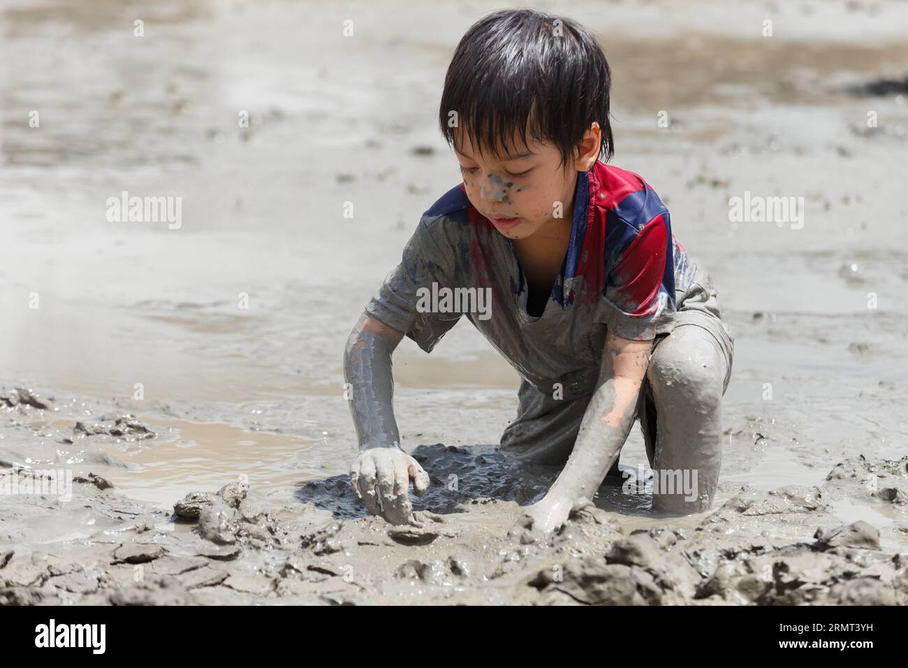 cute happy asian little boy enjoying to play in the mud at playground ...